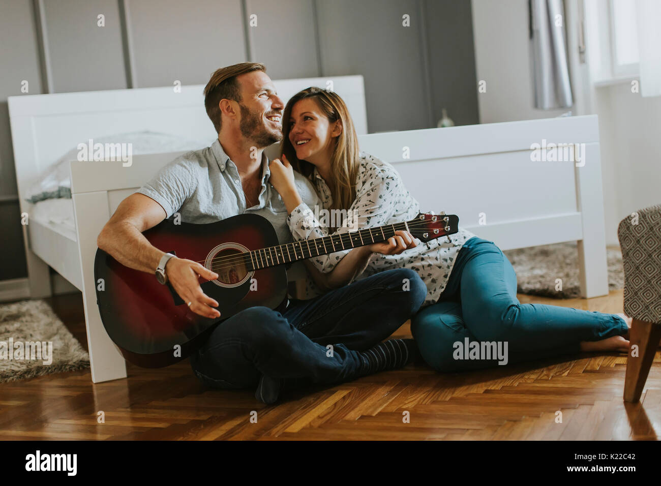 Romantic pair playing guitar on floor in bedroom Stock Photo - Alamy