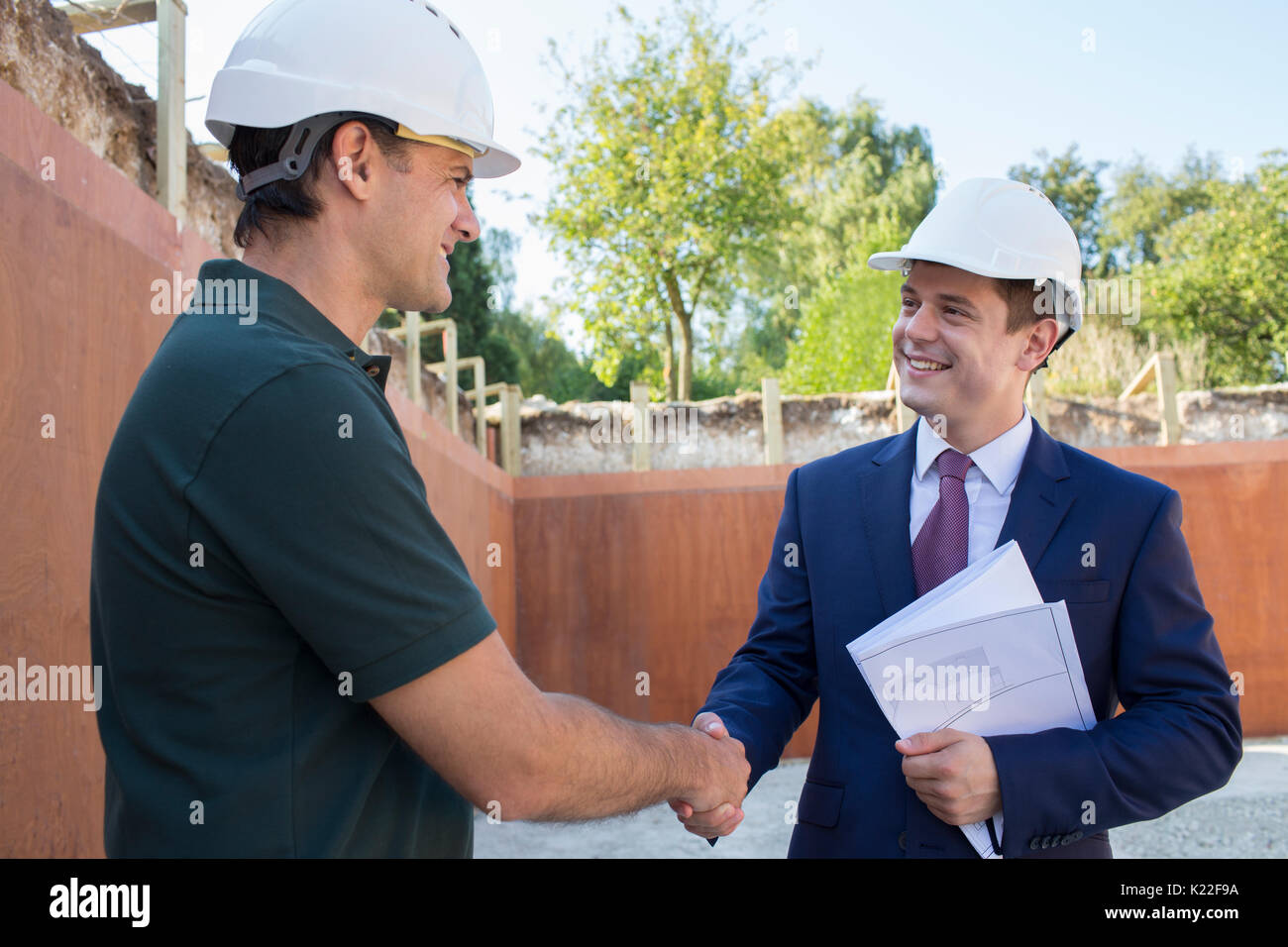 Businessman Shaking Hands With Builder On Construction Site Stock Photo ...