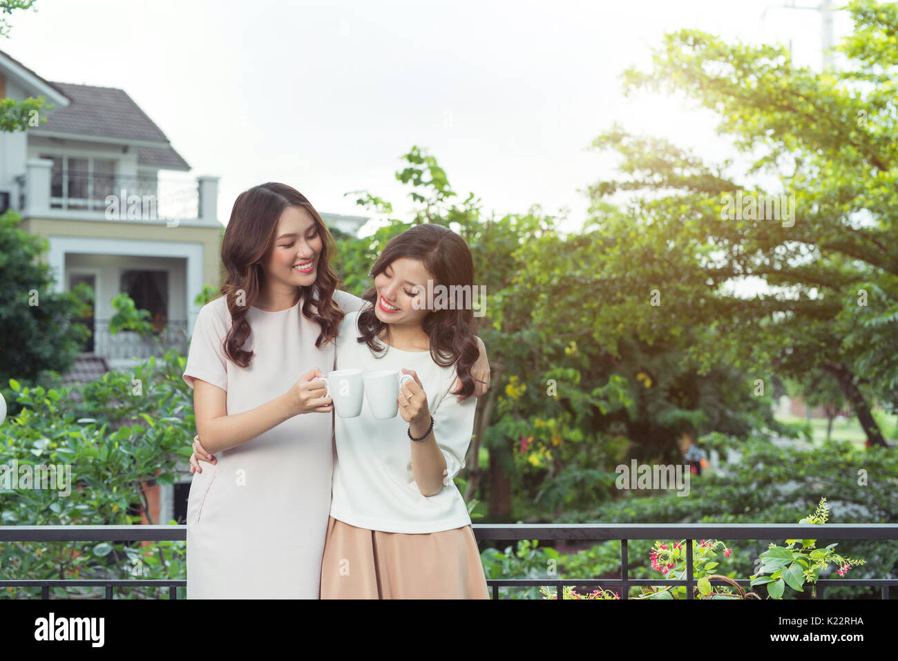 Happy young women friends well-dressed smiling while standing together ...