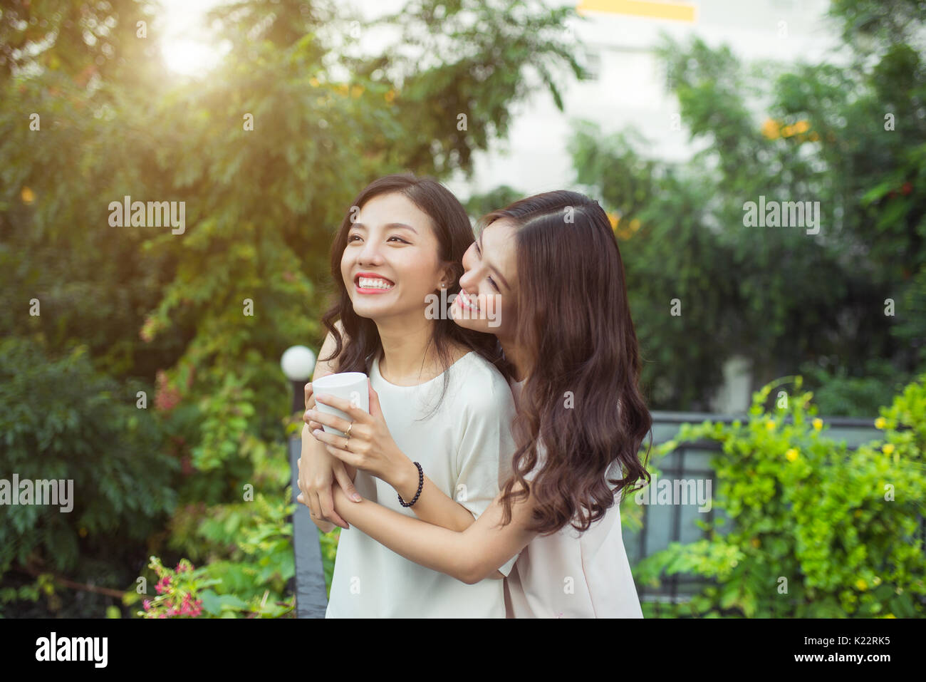 Happy young women friends well-dressed smiling while standing together ...