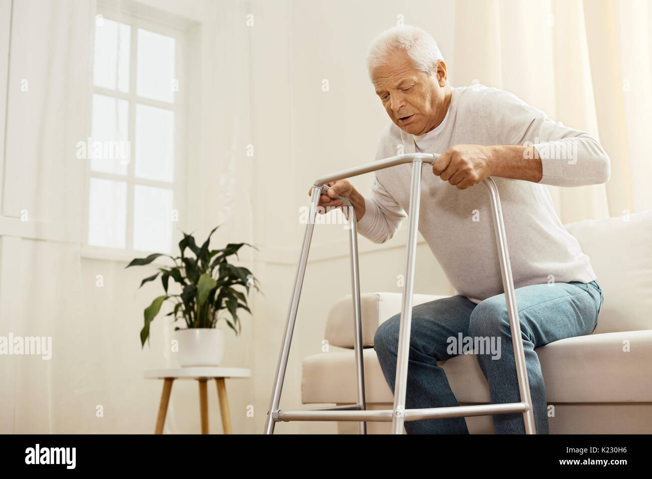 Nice persistent man standing up from the sofa Stock Photo - Alamy