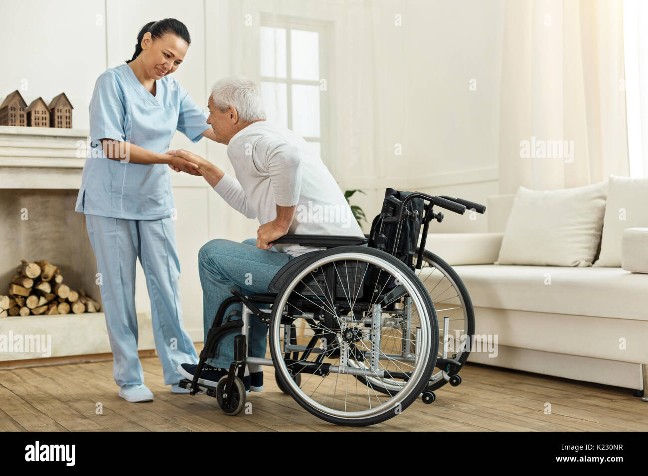 Joyful helpful caregiver holding her patients hand Stock Photo - Alamy