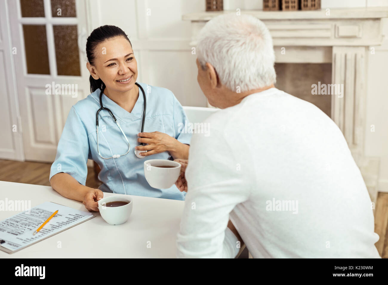 Joyful positive caregiver having tea with her patient Stock Photo - Alamy
