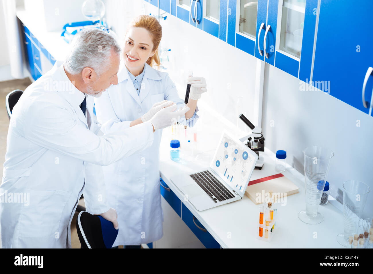 Positive lab assistant showing black reagent to her colleague Stock ...