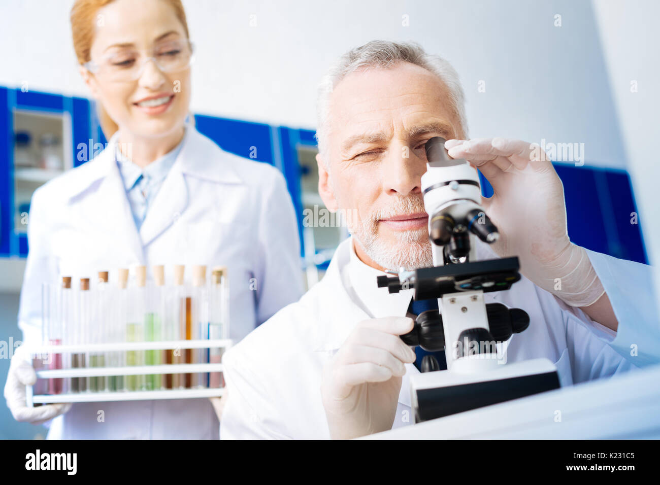 Portrait of positive scientist that looking into microscope Stock Photo ...