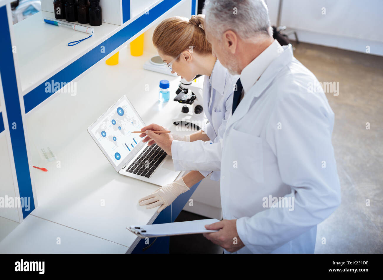 Serious lab assistant looking at screen of computer Stock Photo - Alamy