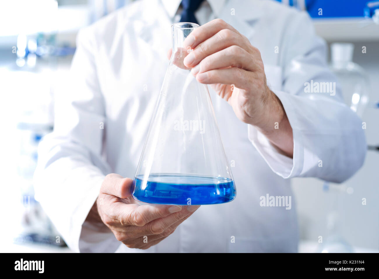 Careful male person showing blue reagent Stock Photo - Alamy