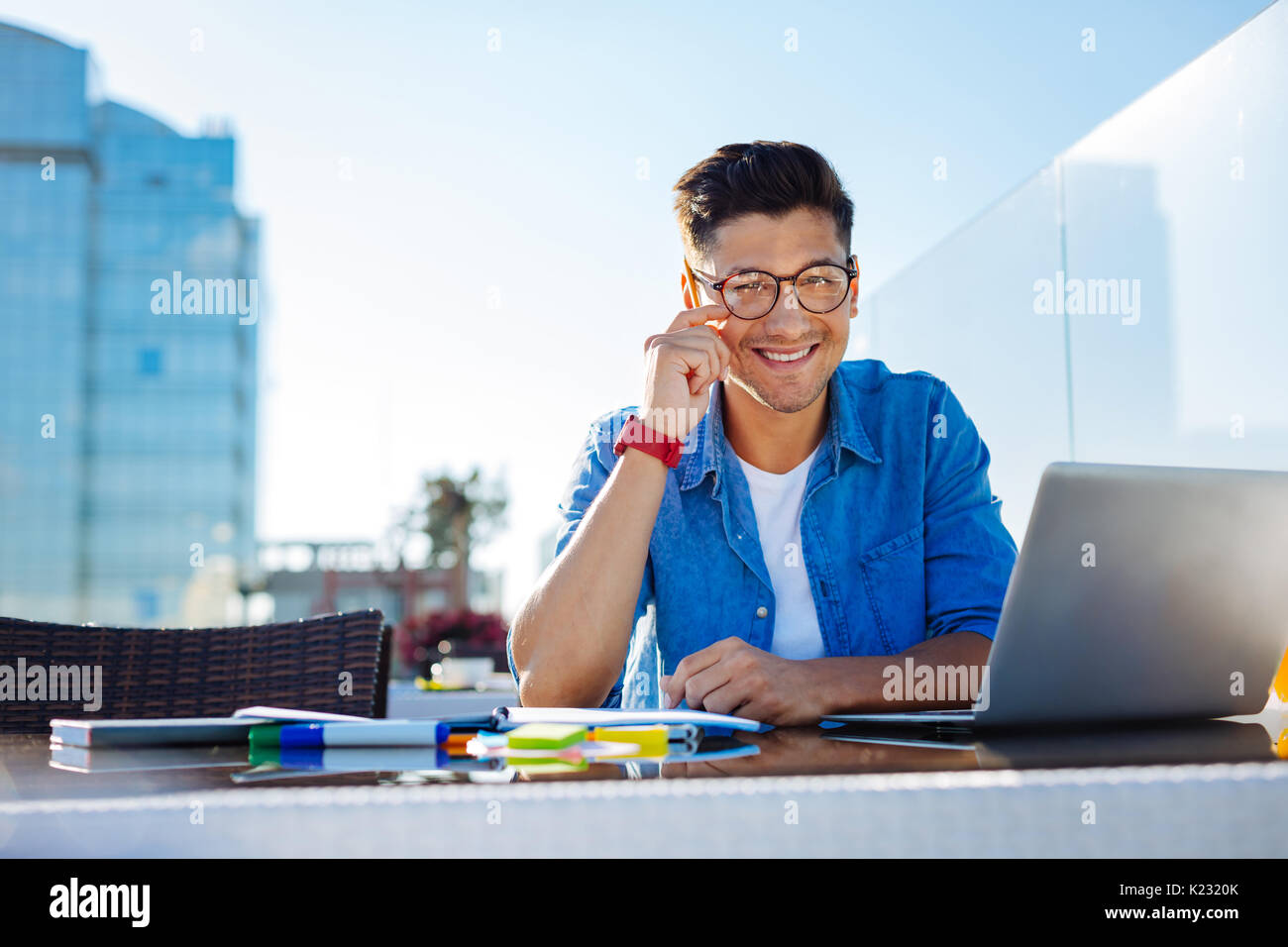 Charming college guy smiling into camera while working on hometask ...