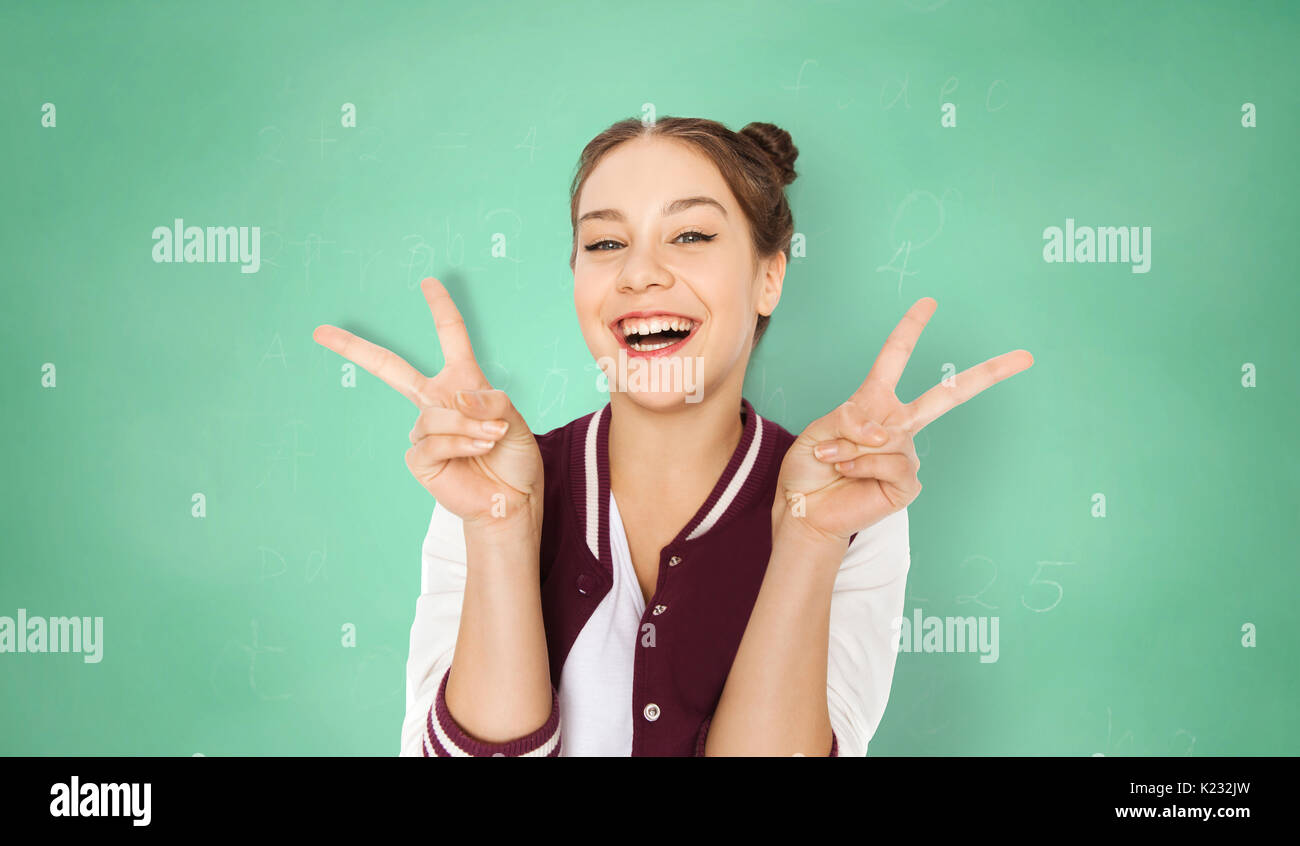 happy student girl showing peace sign over green Stock Photo - Alamy