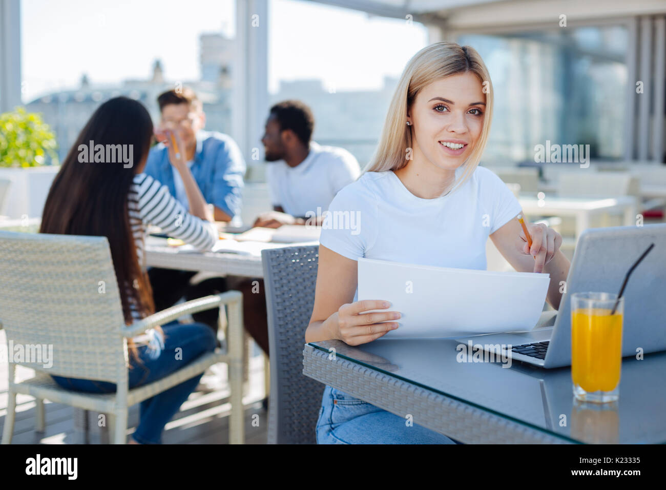 Female student smiling for camera while studying Stock Photo - Alamy