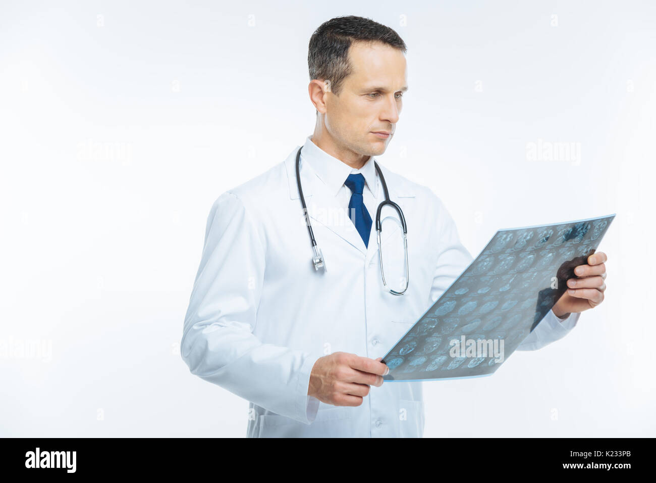 Serious male physician looking at mri scan of patient head Stock Photo ...