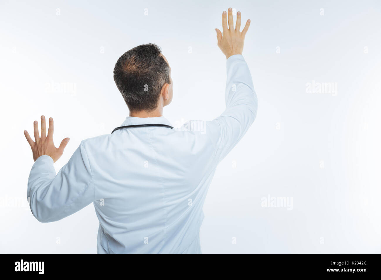 Turned back doctor holding hands on invisible screen Stock Photo - Alamy