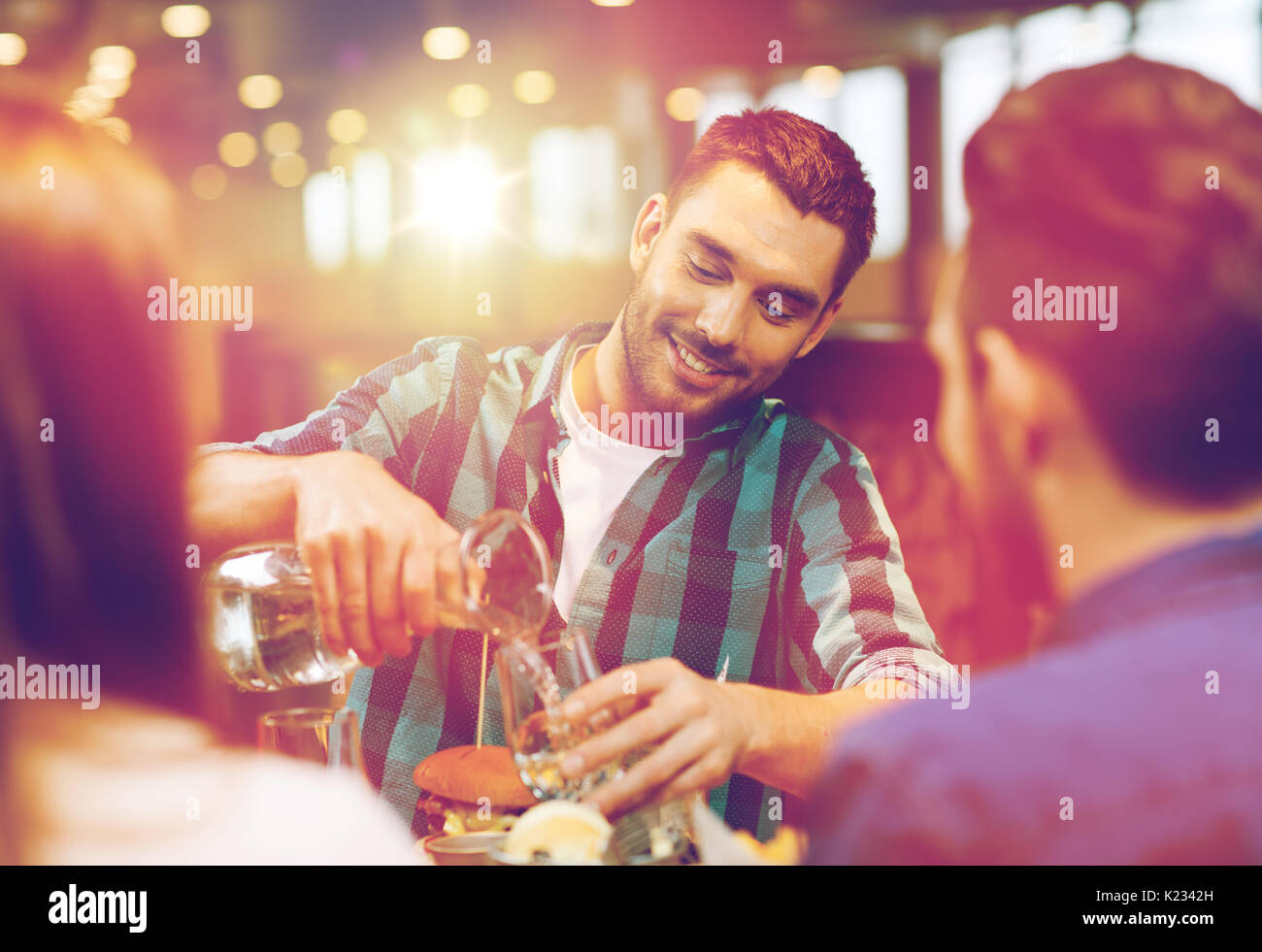 happy man with friends pouring water at restaurant Stock Photo - Alamy