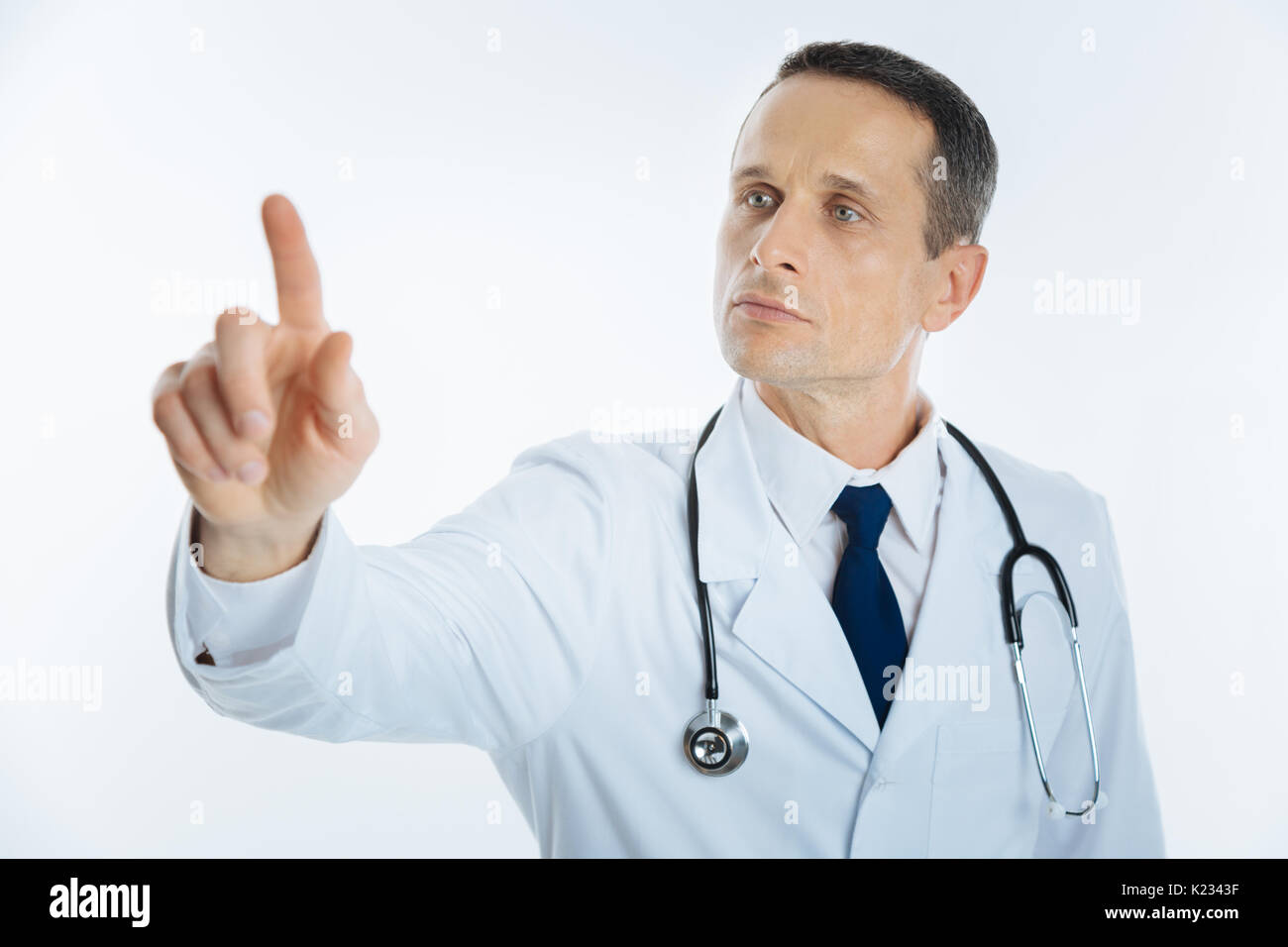 Serious mature doctor using invisible touchscreen alone Stock Photo - Alamy