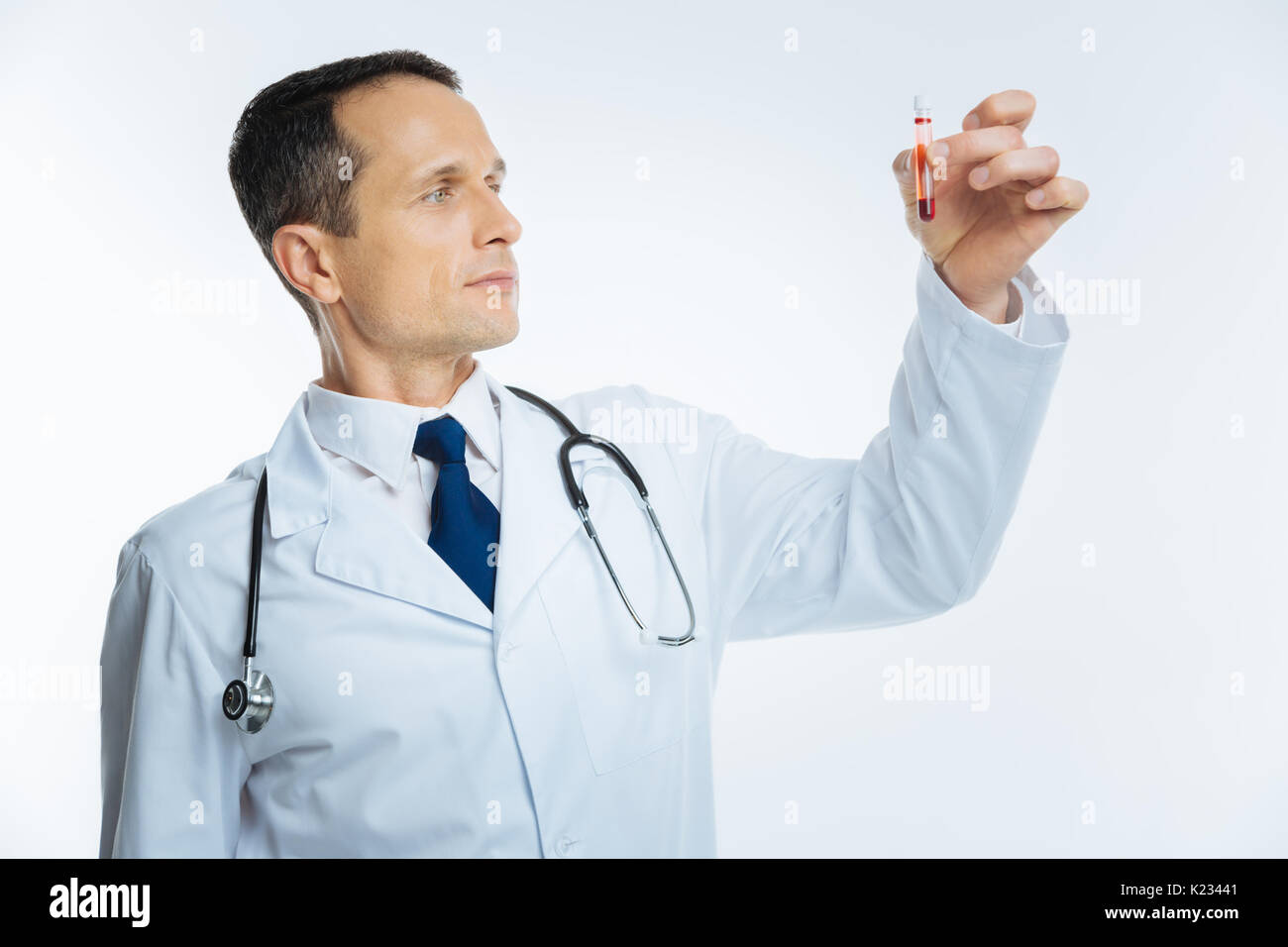 Serious male doctor looking at blood sample Stock Photo - Alamy