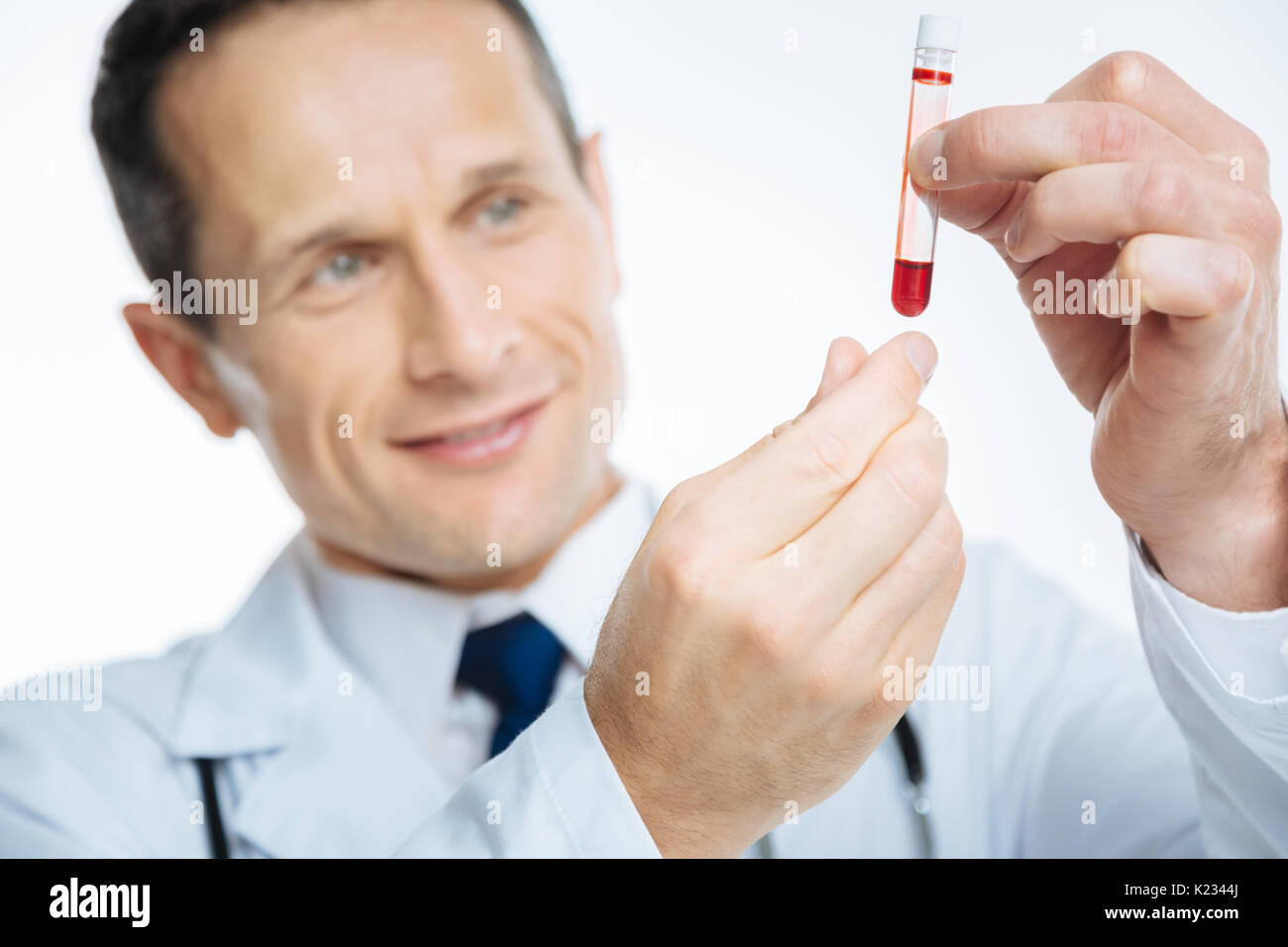 Smiling doctor looking at blood sample Stock Photo - Alamy