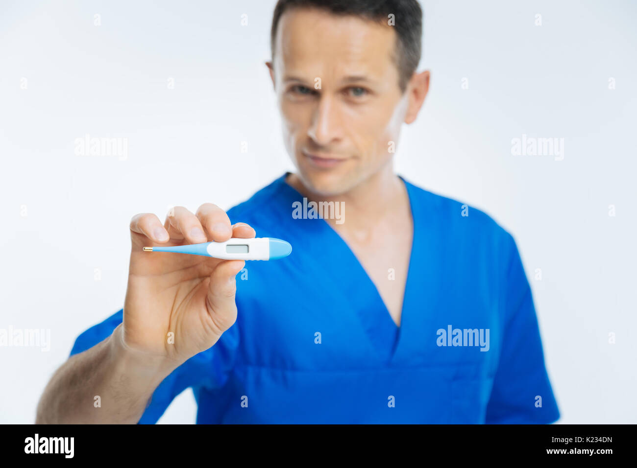Handsome doctor showing thermometer into camera Stock Photo - Alamy