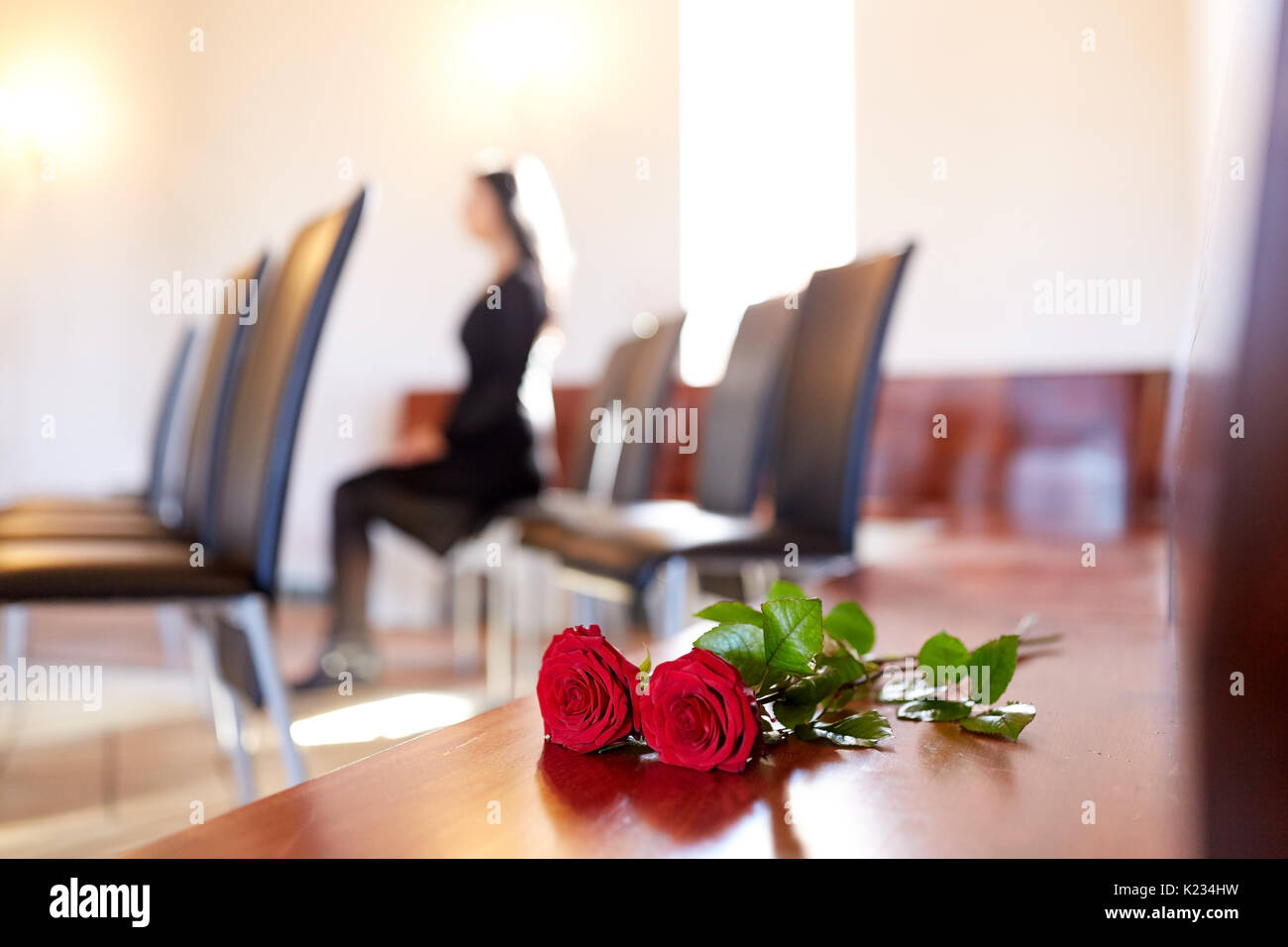 red roses and woman crying at funeral in church Stock Photo - Alamy