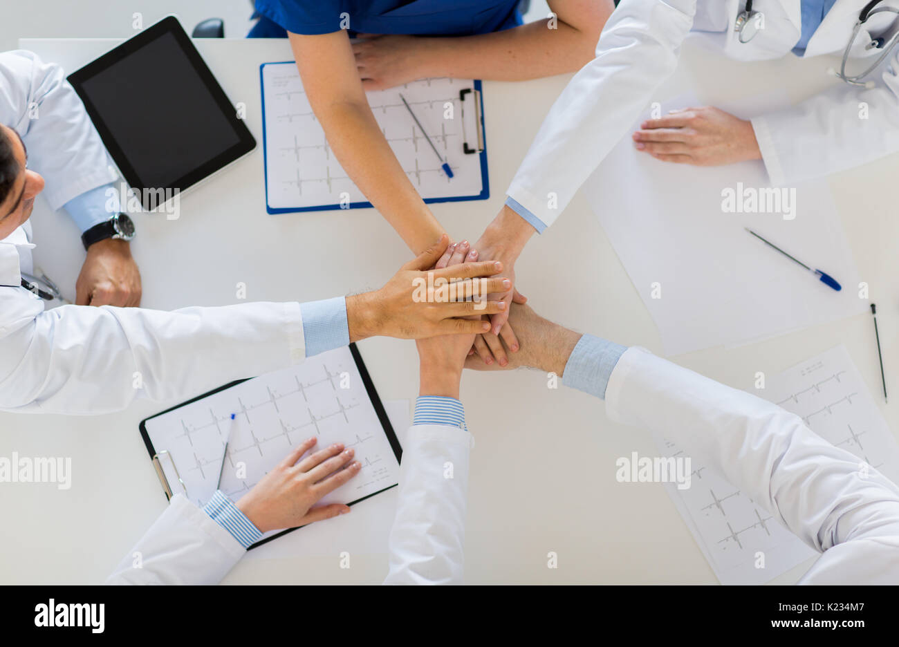 group of doctors holding hands together at table Stock Photo - Alamy