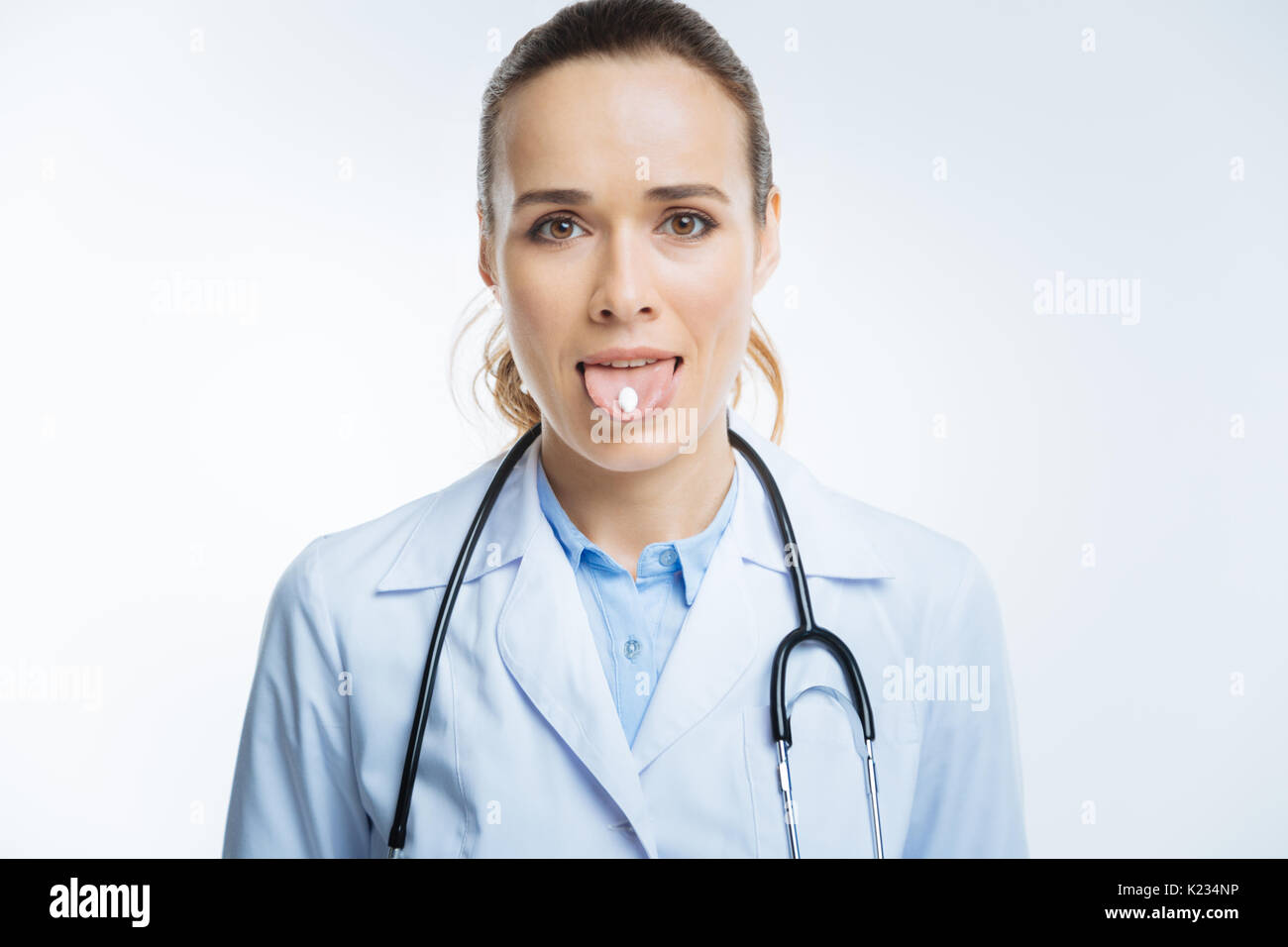 Hazel eyed doctor holding pill on her tongue Stock Photo - Alamy