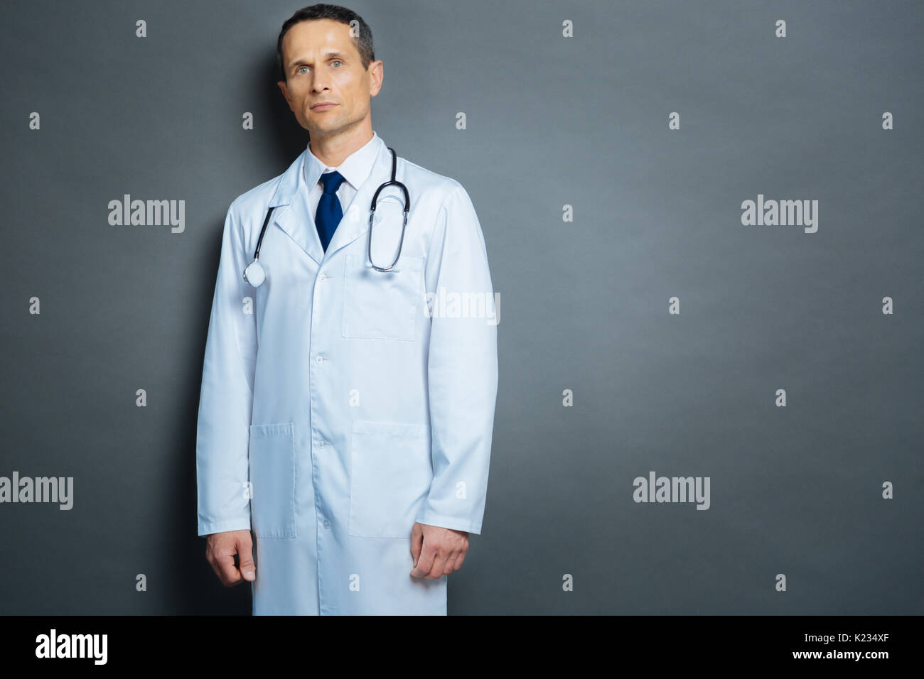 Serious male physician posing for camera over grey background Stock ...