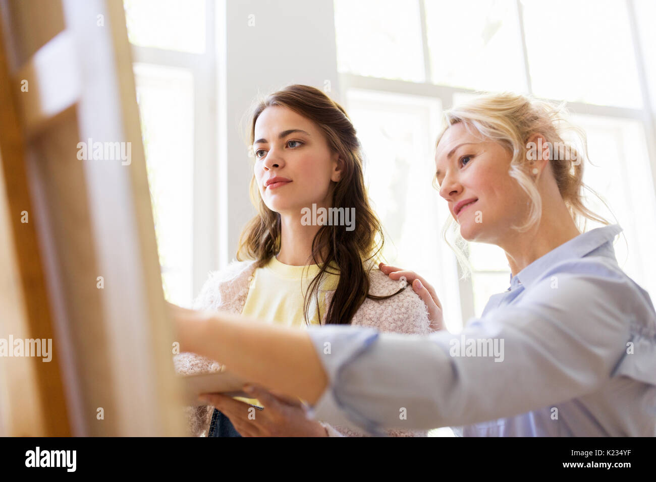 artists discussing painting on easel at art school Stock Photo - Alamy