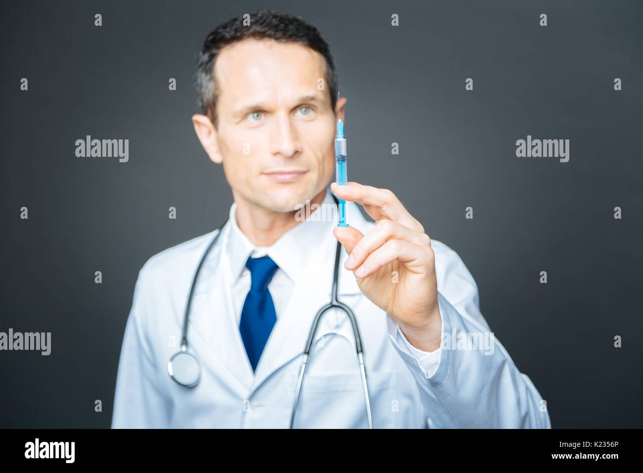 Confident male doctor focusing his attention on syringe Stock Photo - Alamy