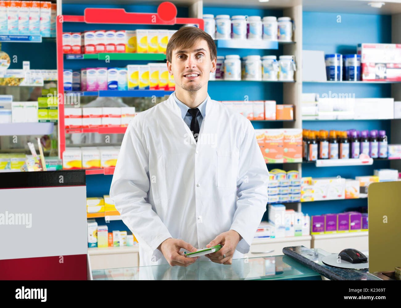 Smiling male pharmacist in white uniform posing in drugstore Stock ...