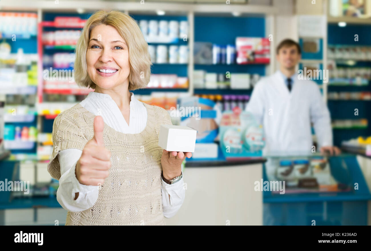 Portrait of happy mature woman chooses drugs at the pharmacy Stock ...