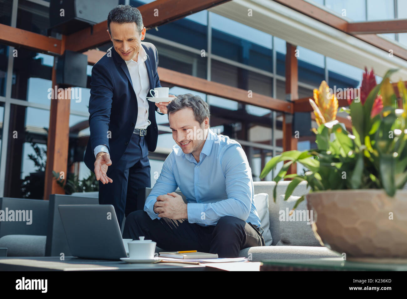 Positive successful businessman standing behind his colleague Stock ...