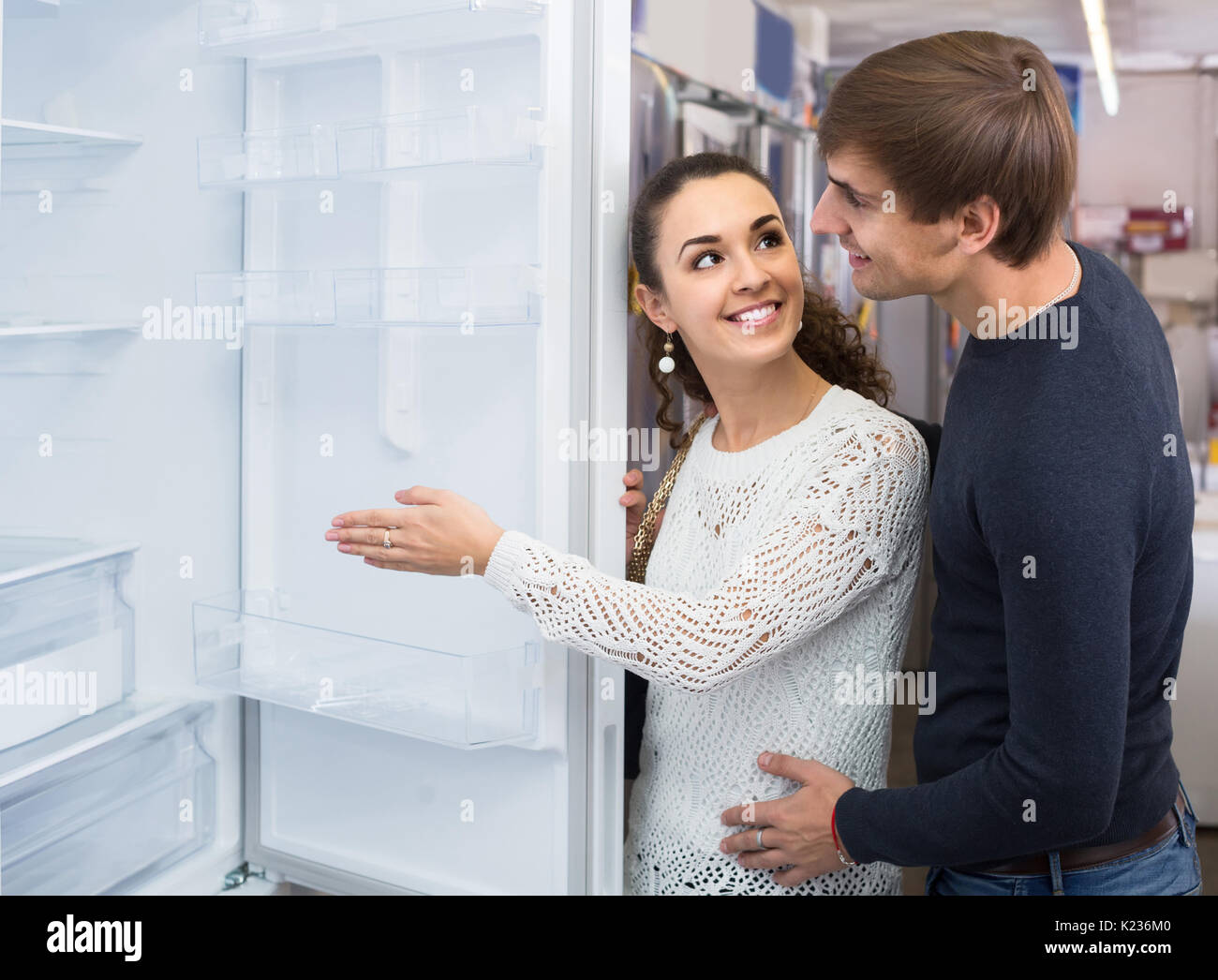 smiling russian family couple choosing new refrigerator in hypermarket ...