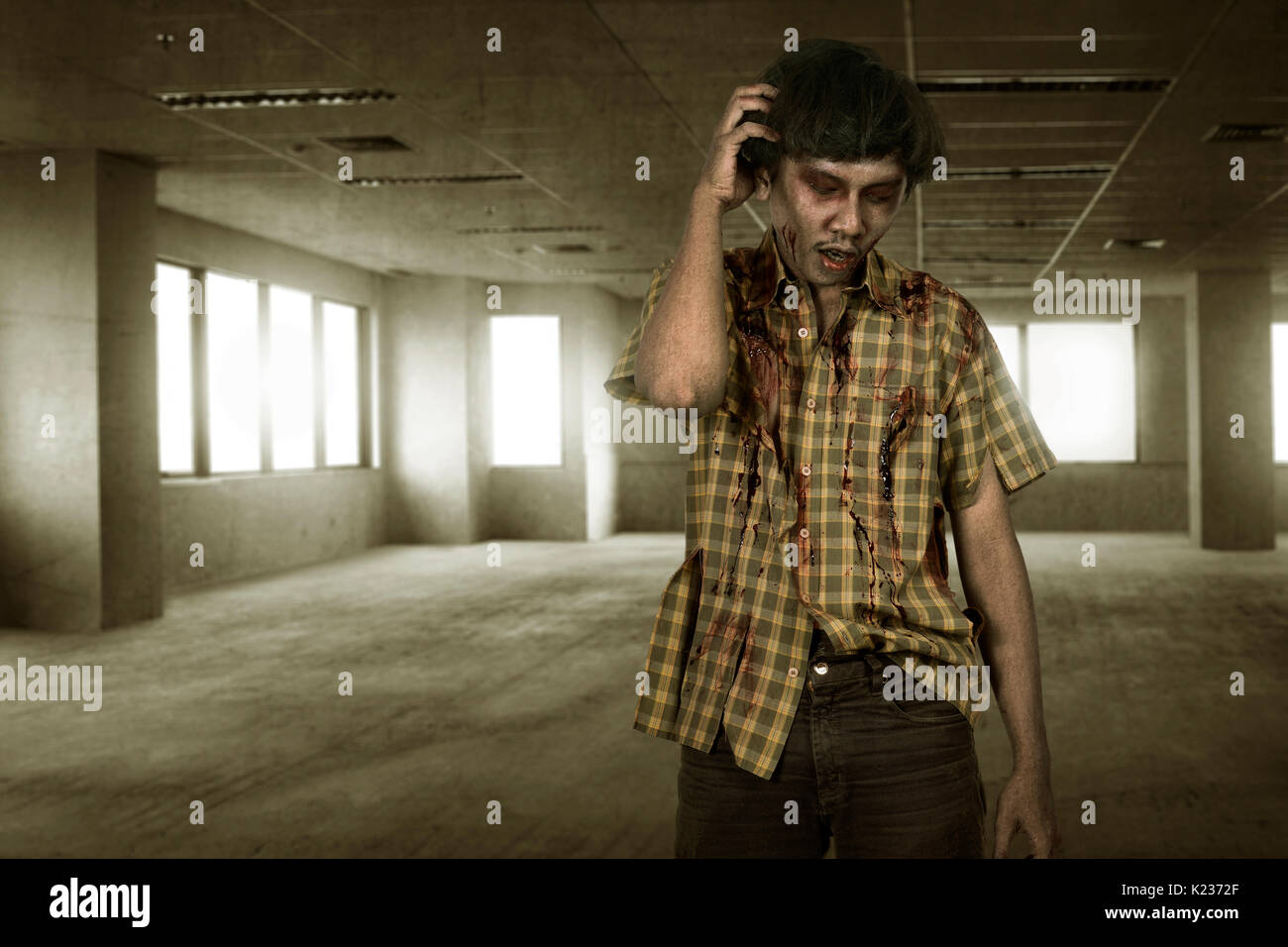 Scary asian zombie man with wounded face standing on the empty room ...