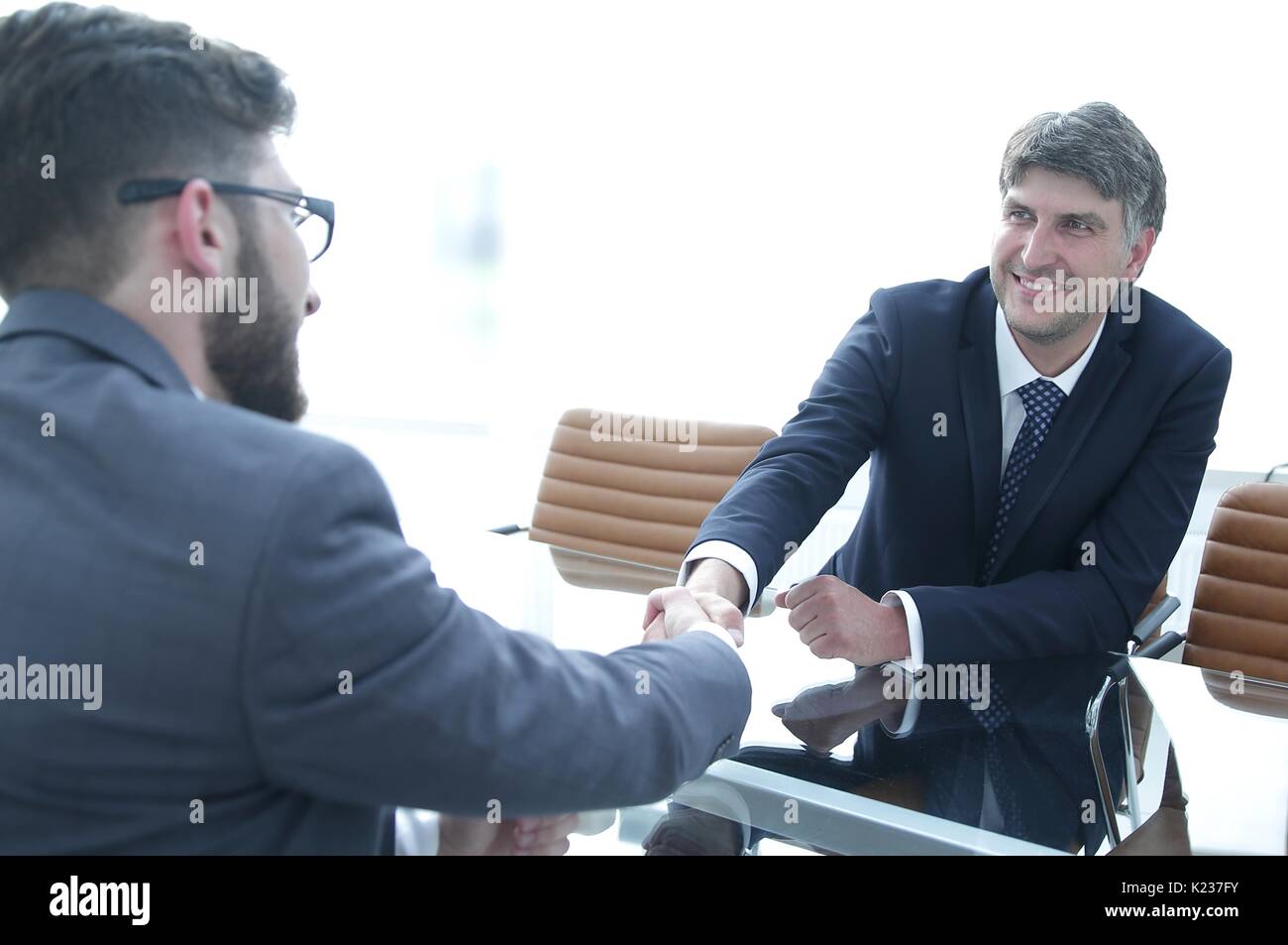 Handshake across the table of financial partners Stock Photo - Alamy