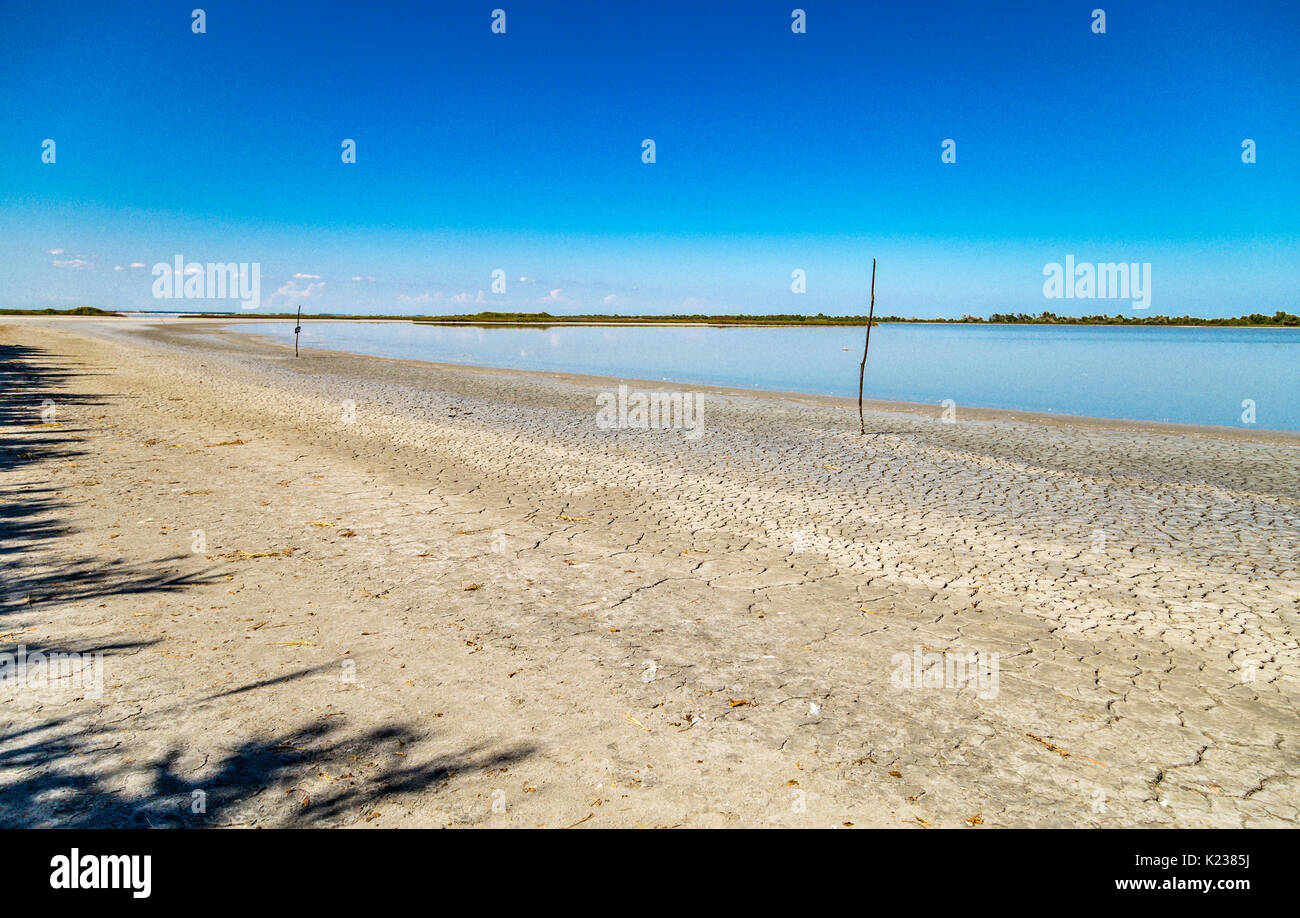 cracked clay soil beach on clear lagoon water Stock Photo - Alamy