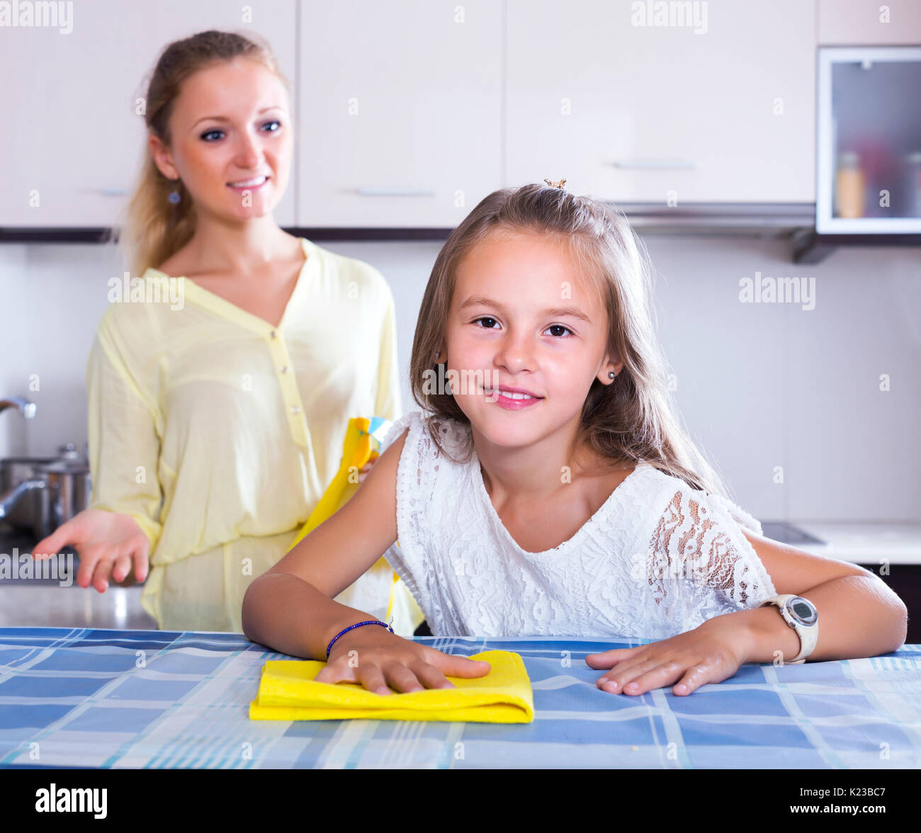 Little positive girl helping adult mom dusting in the kitchen Stock ...