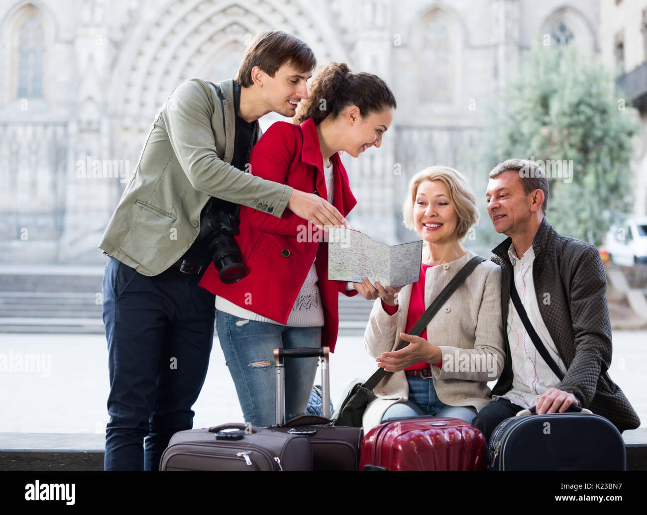 Group of tourists looking for the right direction with map and baggage ...