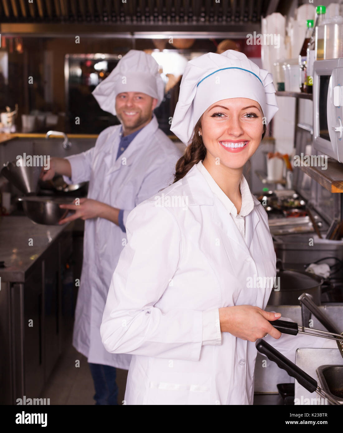 Positive handsome cooks greeting customers at bistro kitchen and ...