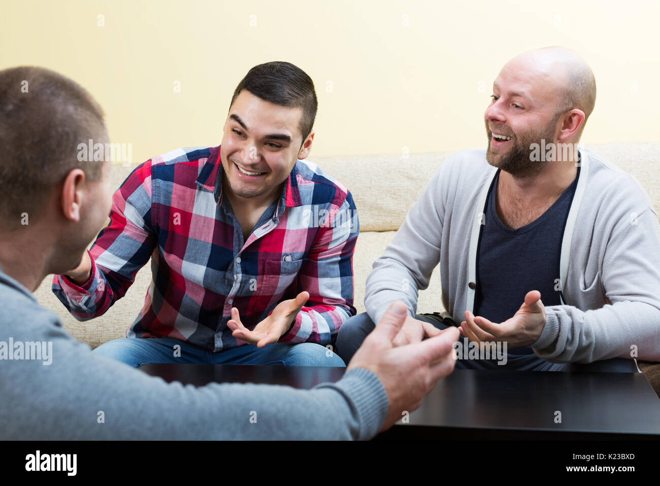 Three men talking and laughing at living room Stock Photo - Alamy