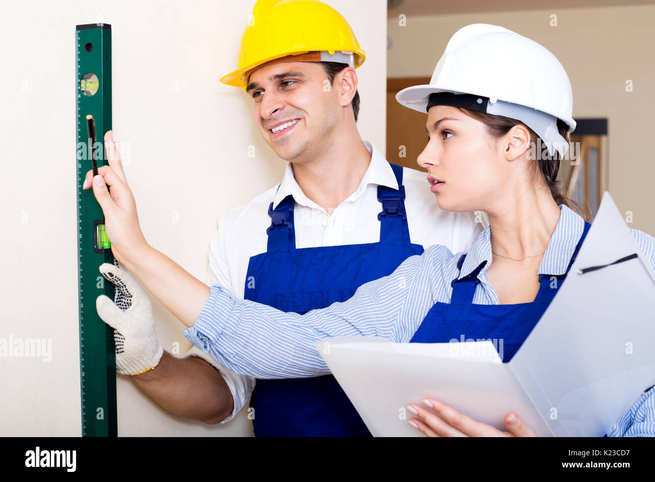 Happy female constructor showing assistant measuring the wall indoors ...