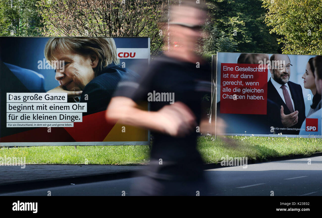 Cologne, Germany. 28th Aug, 2017. A man runs past campaign posters with ...