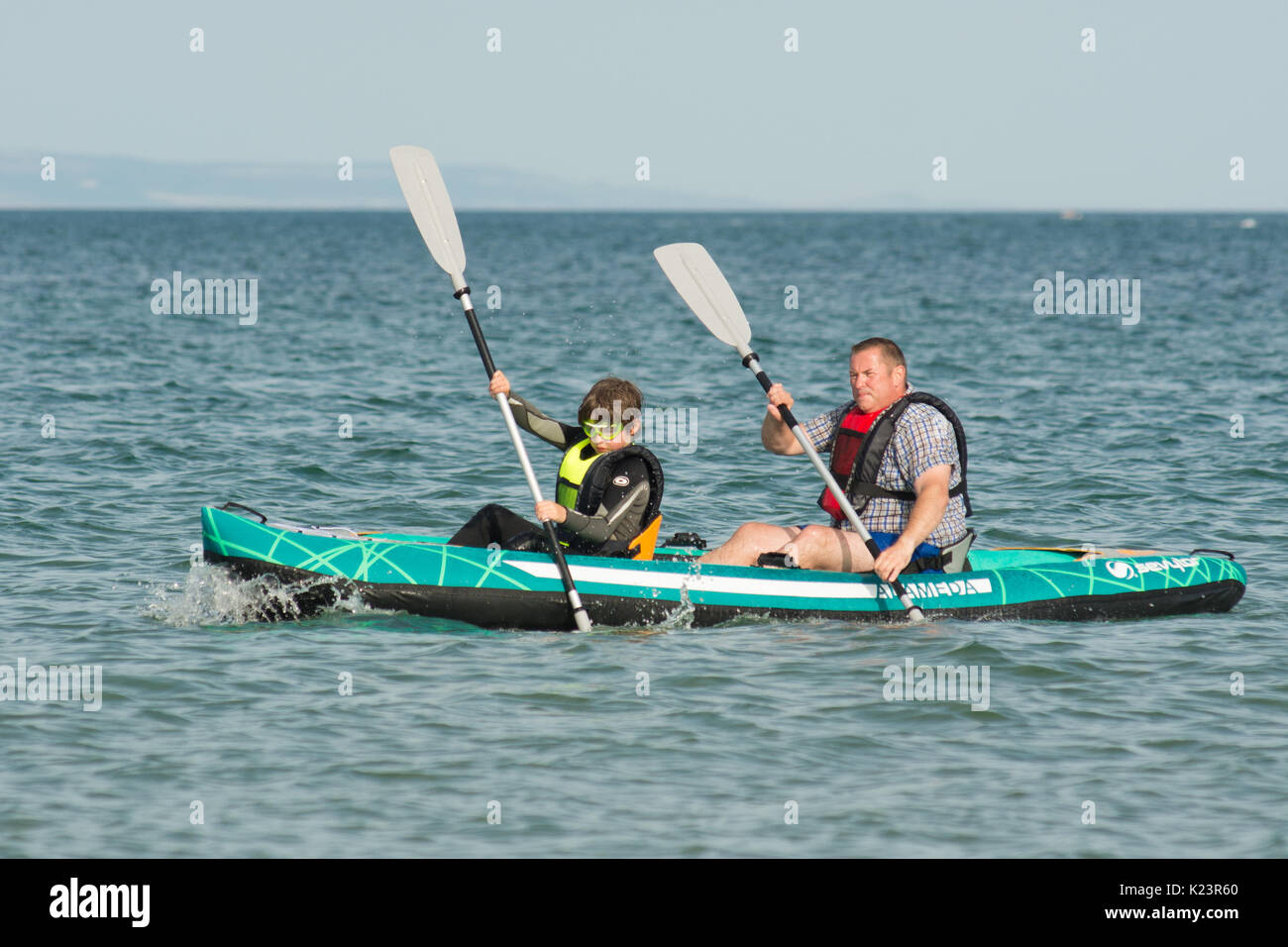 Man and boy paddling in inflatable kayak on the sea, Dorset, UK Stock ...