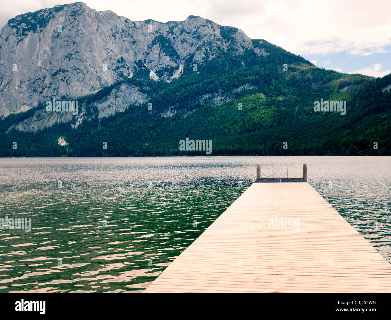 Mountain lake with small wooden jetty, pier mole, wind sleeve. Alpine ...