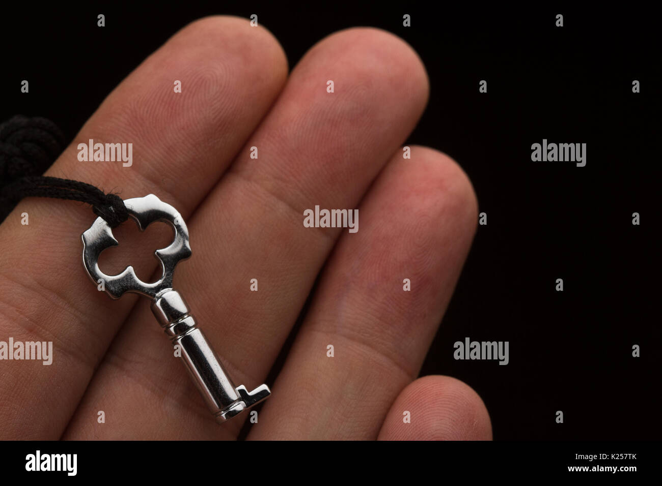 top view closeup of Caucasian hand holding a small silver lock key with ...