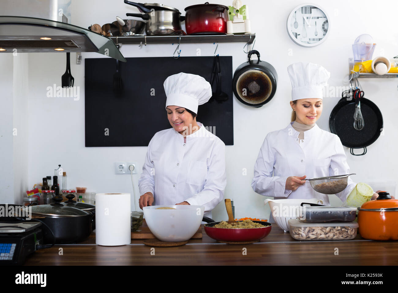 Happy women chefs cooking food at cafe's kitchen Stock Photo - Alamy