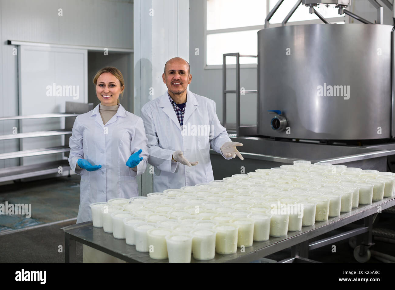 cheerful man and woman wearing uniform working on cottage cheese ...