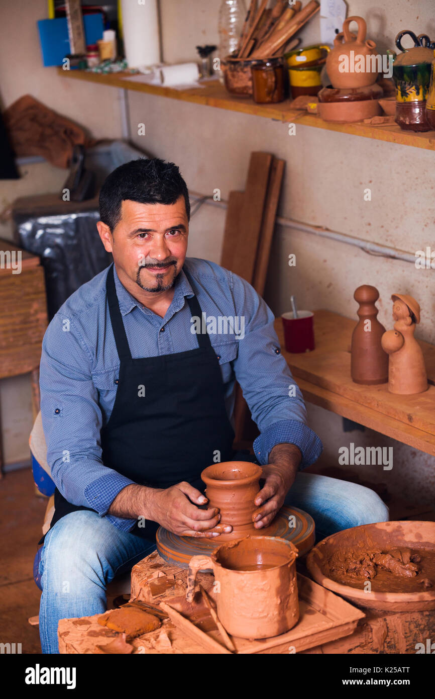 Positive mature man making pot using pottery wheel in studio Stock ...
