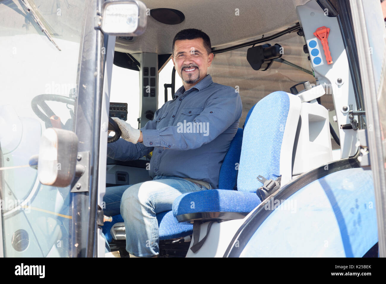 Cheerful driver sitting in big field engine on farm Stock Photo - Alamy
