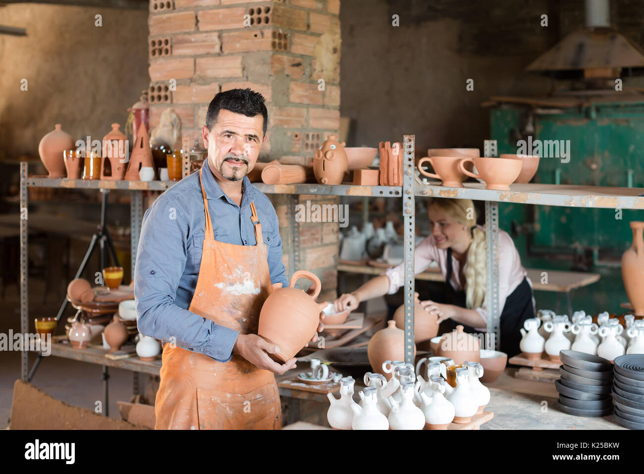 Smiling american man potter holding ceramic vessels in atelier Stock ...