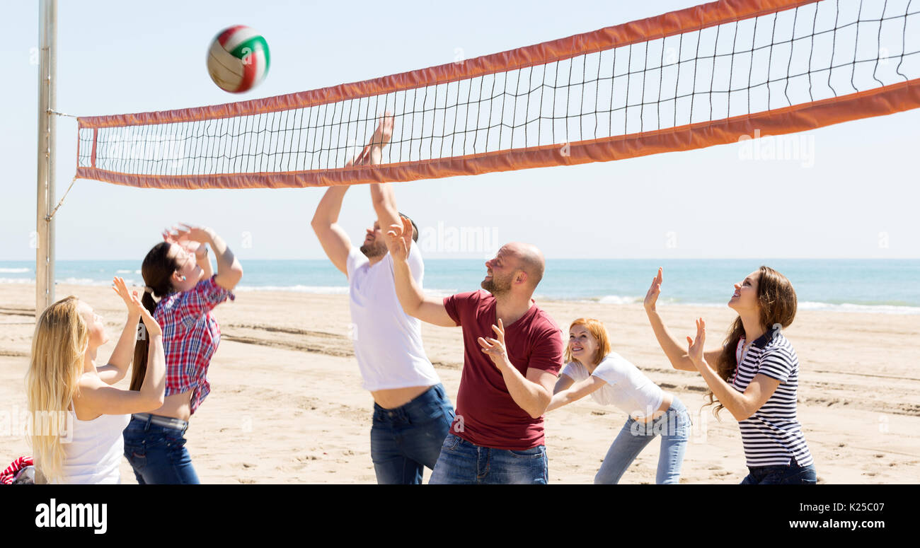 positive people throwing ball over net and laughing. Focus on the right ...
