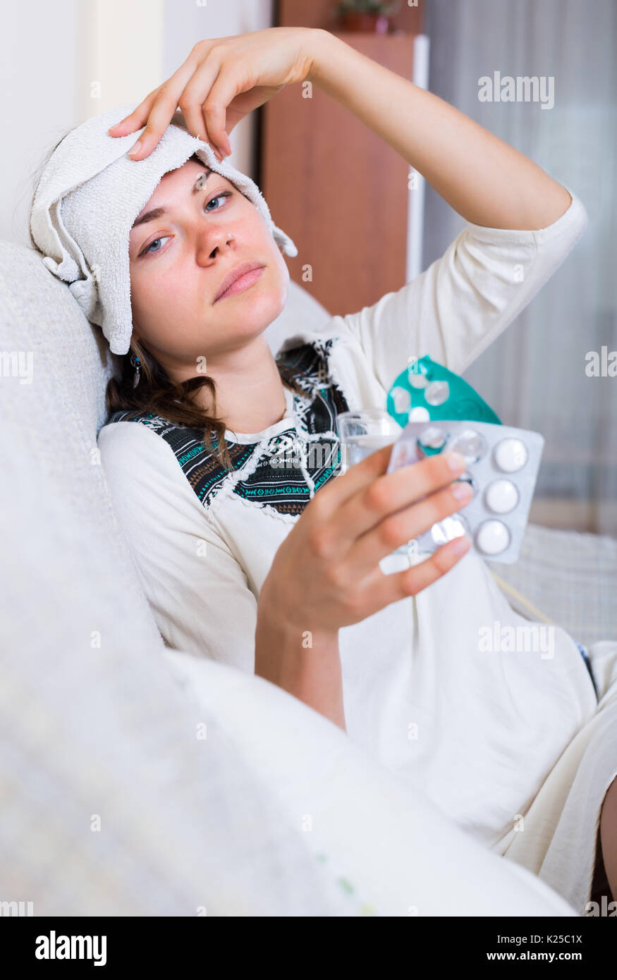Tired woman with cold application and headache at home Stock Photo - Alamy